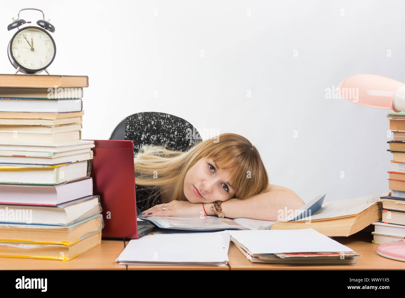 Girl student lay behind a desk crammed with books and papers Stock ...