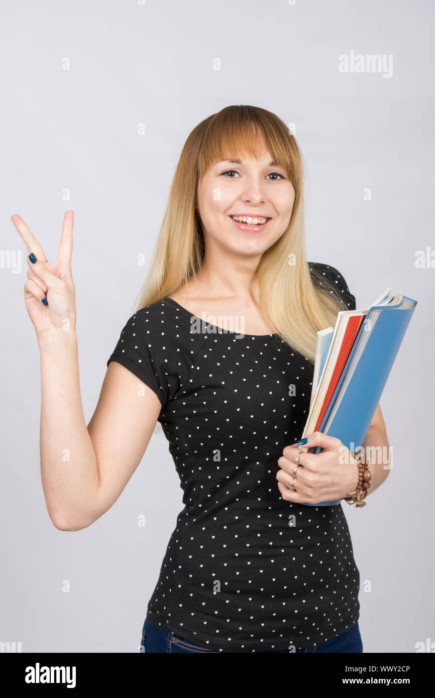 The joyful girl with a folder in his hands shows gesture quot ...