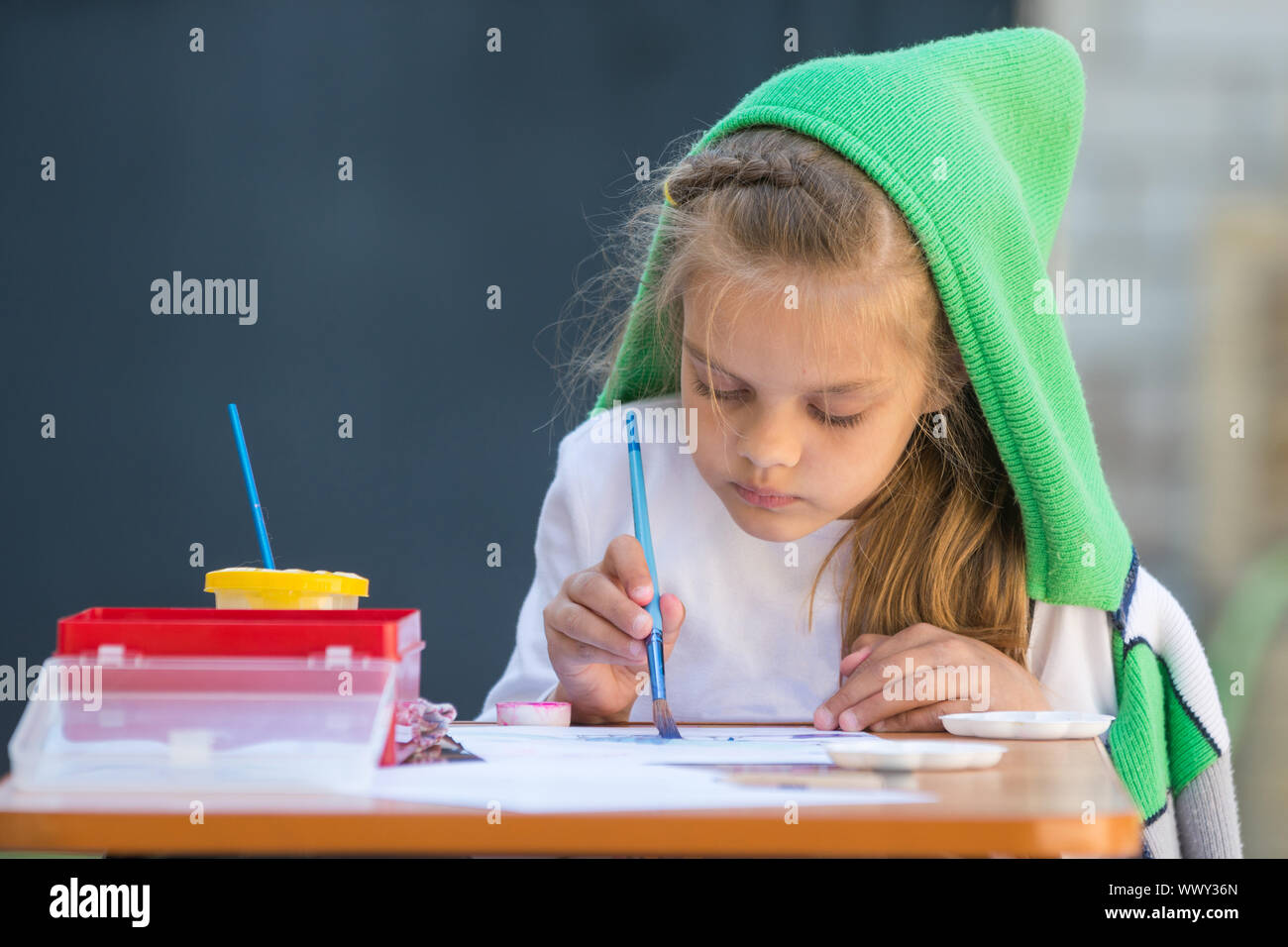 Slightly disheveled girl watercolor paints sitting at the table in the ...