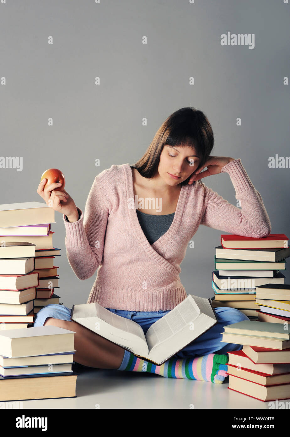 Cute girl studying with a big stack of books Stock Photo - Alamy