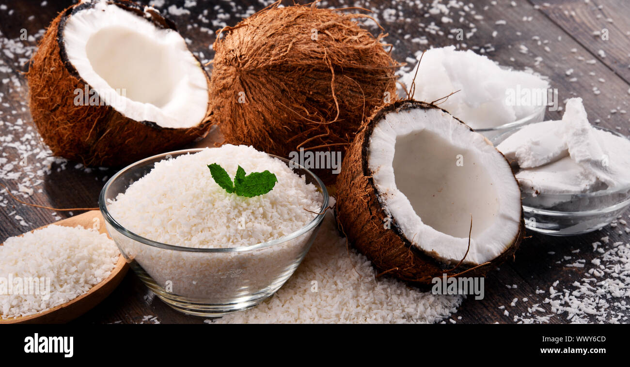 Composition with bowl of shredded coconut and shells on wooden table ...
