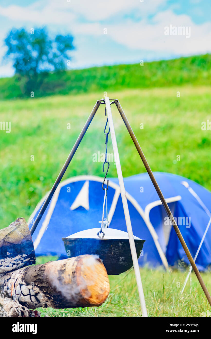 a camp-steaky sooty food bowl hanging on a tripod over a fire Stock ...