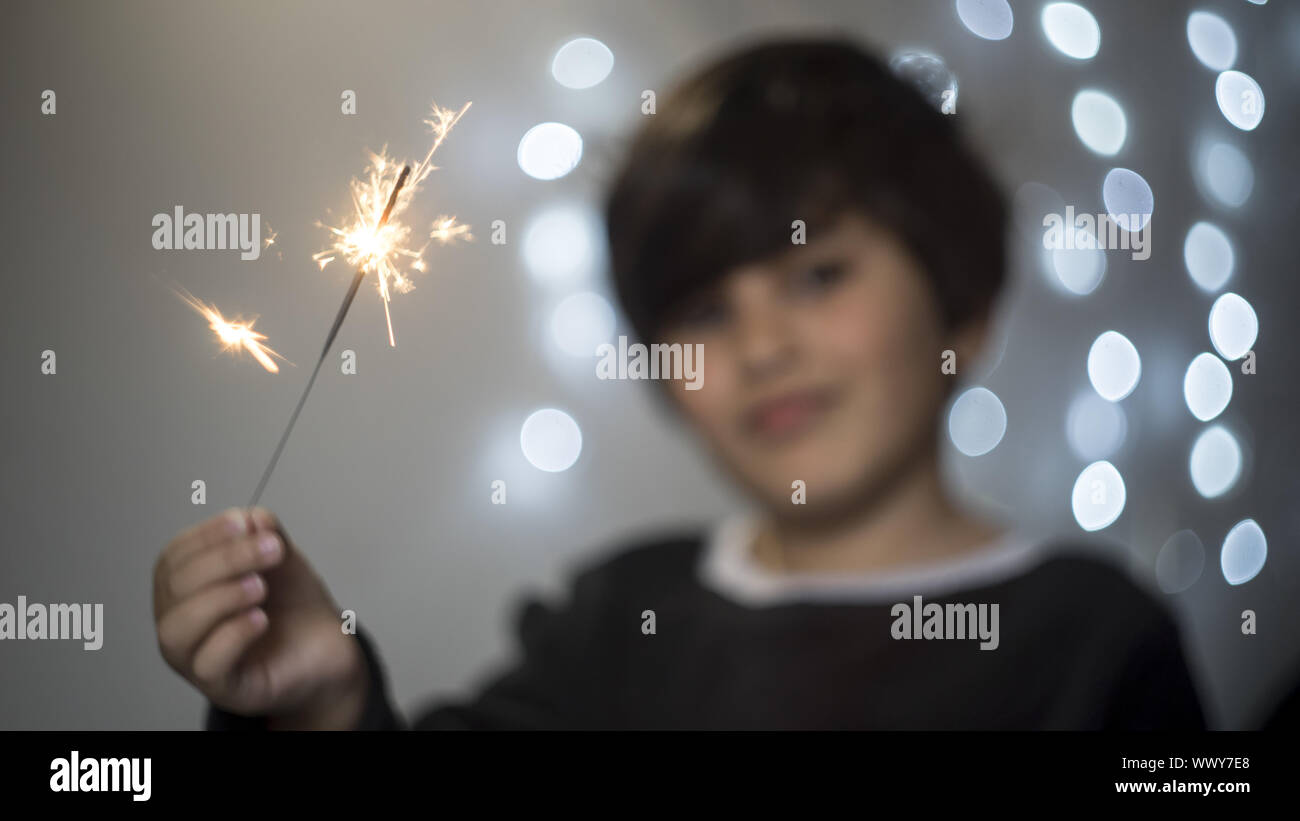 fireworks, child with flares of lights and Christmas lights in the ...