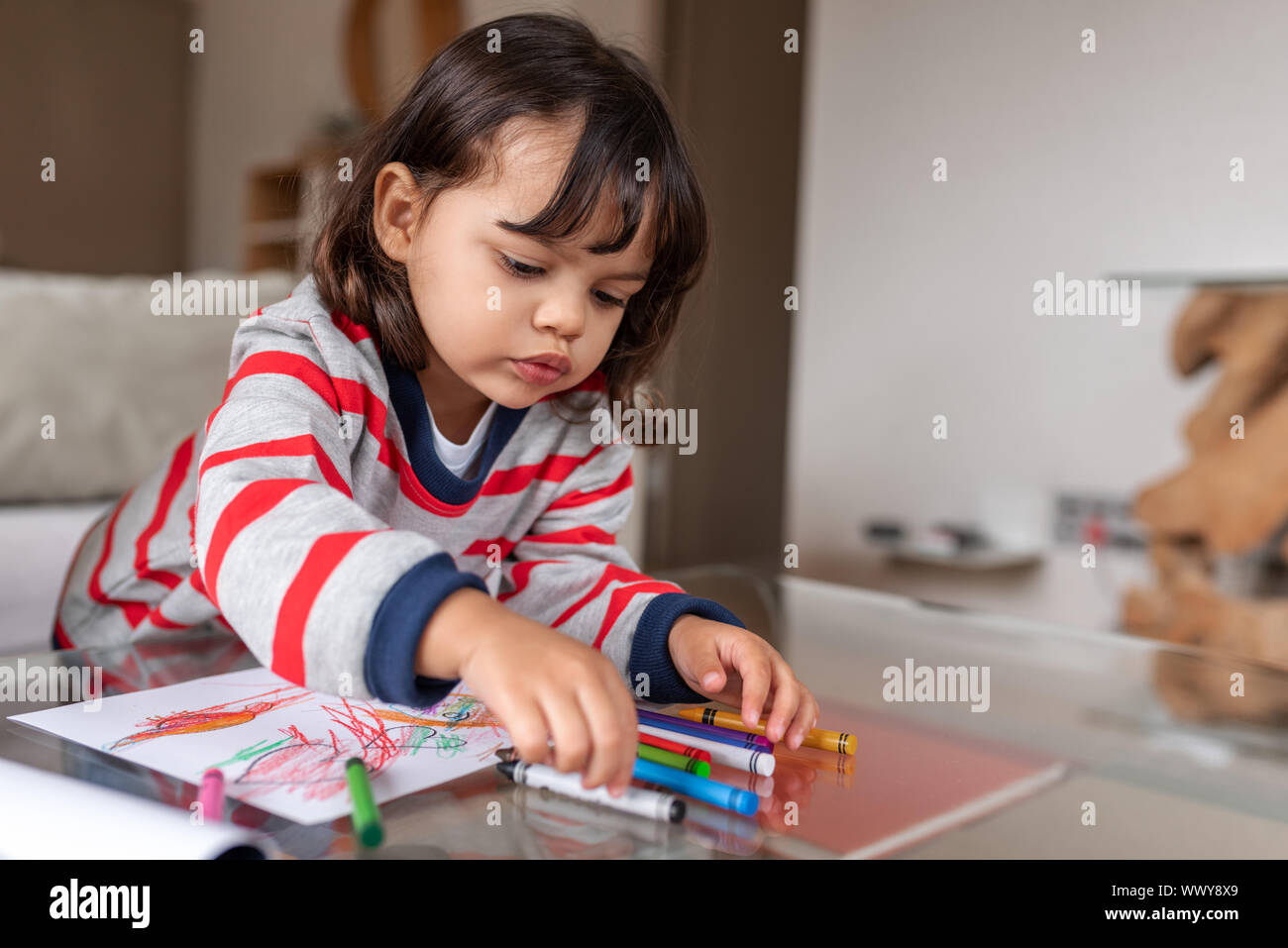 Adorable little girl coloring with crayons at home Stock Photo - Alamy
