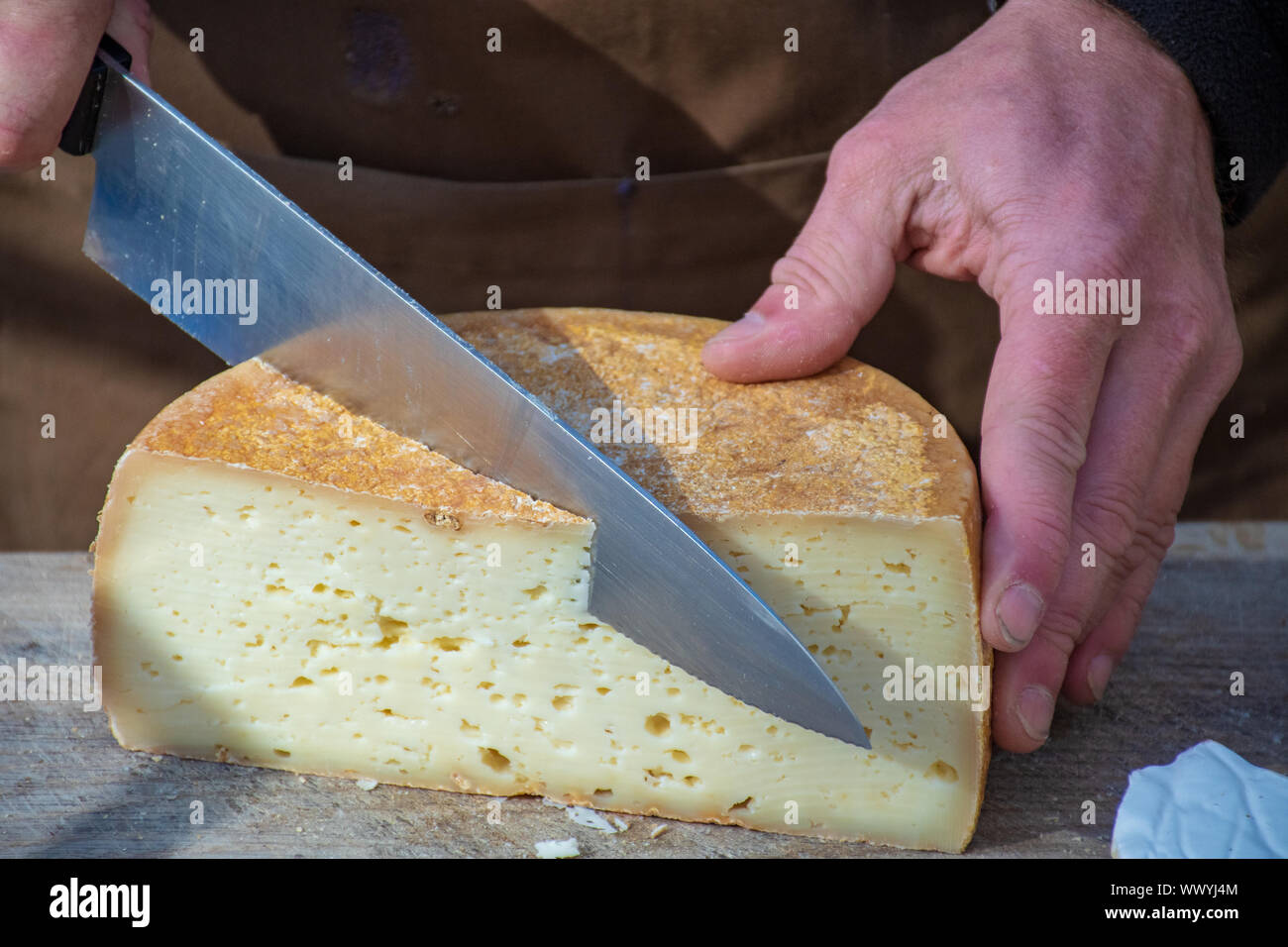 Men cutting with a knife homemade bio natural cheese in a street food ...