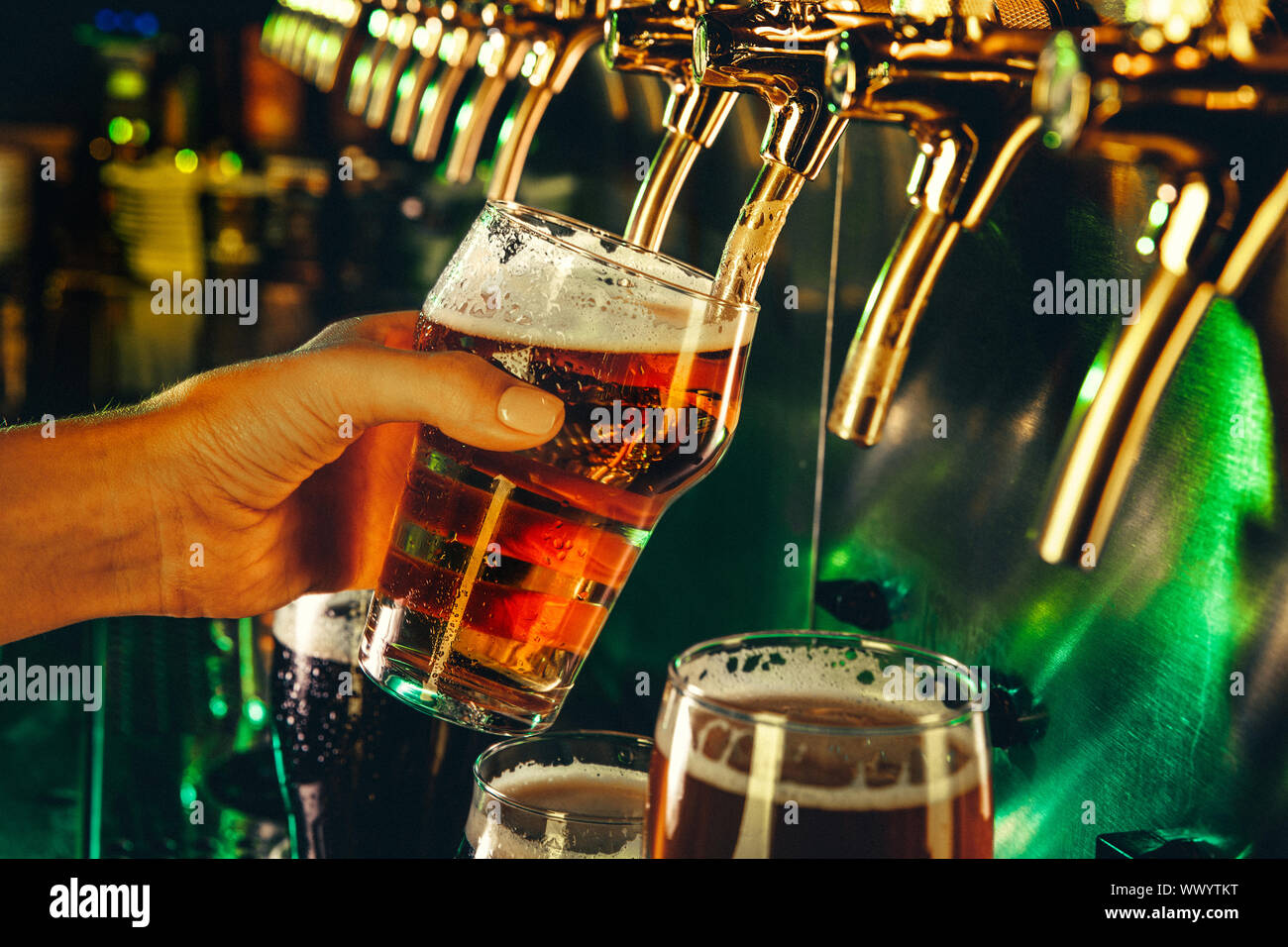 Hand of bartender pouring a large lager beer in tap. Bright and modern ...