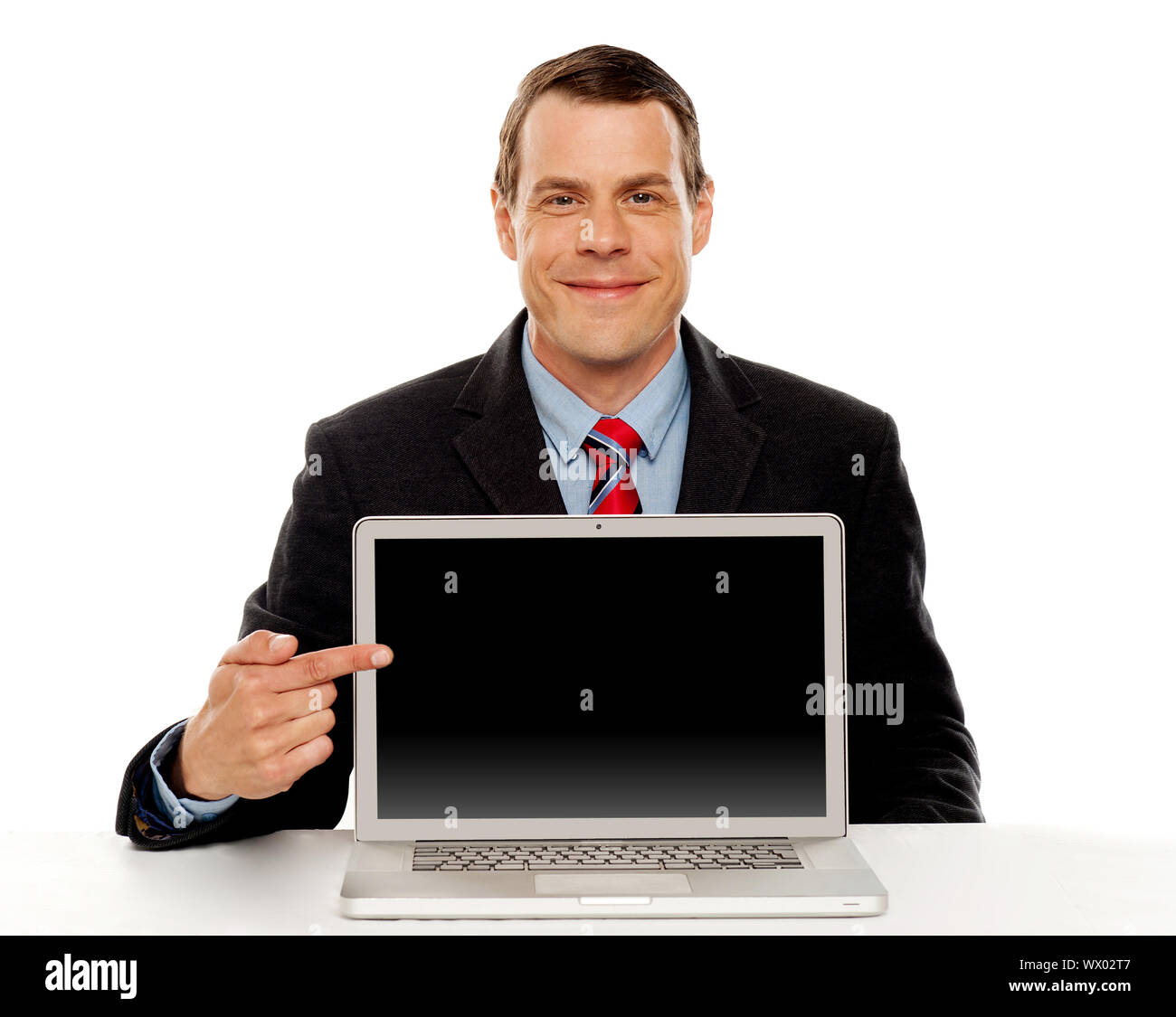 Seated young businessman pointing at blank laptop screen. Laptop facing ...