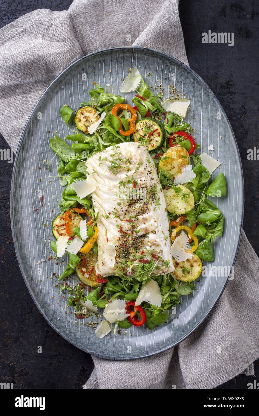Fried cod fish fillet with lettuce and vegetable as top view on a plate ...