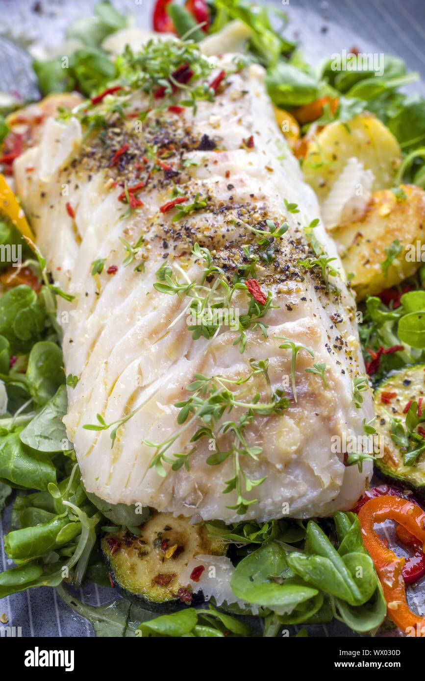 Fried cod fish fillet with lettuce and vegetable as close-up on a plate ...