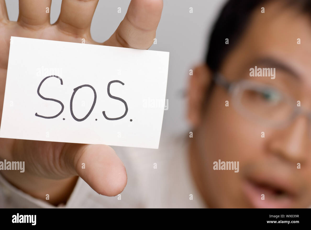 Business man need help and write SOS on white card Stock Photo - Alamy