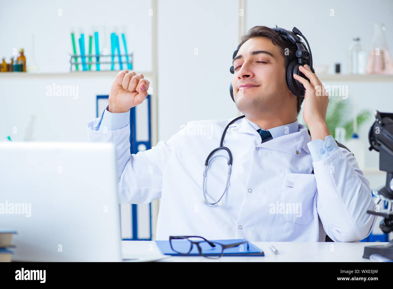Happy excited doctor listening to music during lunch break in hospital ...