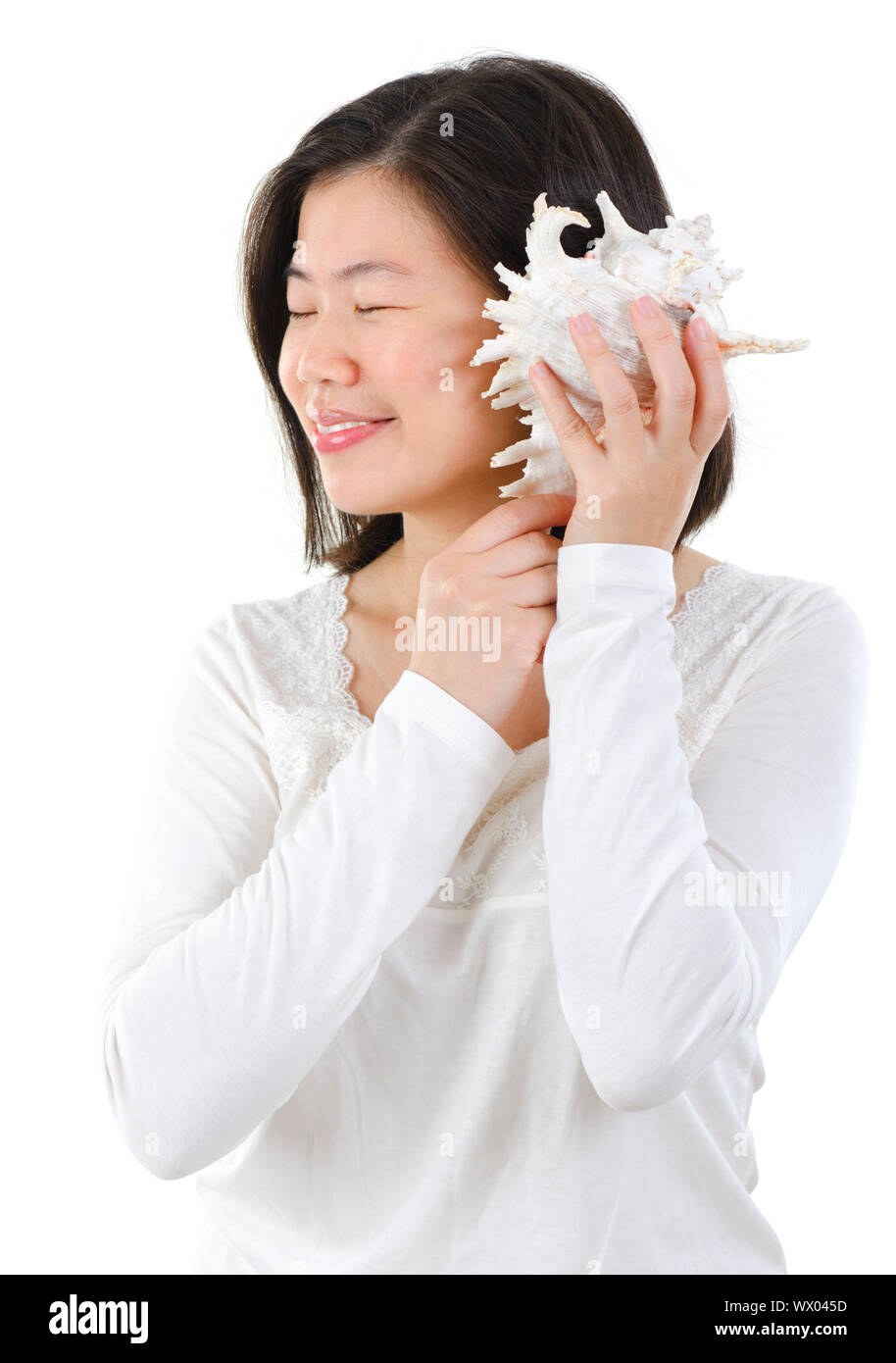 Asian female listening to a seashell over white background Stock Photo ...