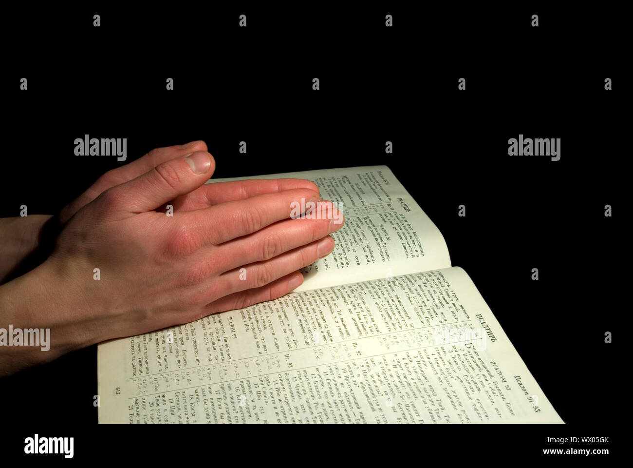 A mans hands clasped in prayer over a Bible Stock Photo - Alamy