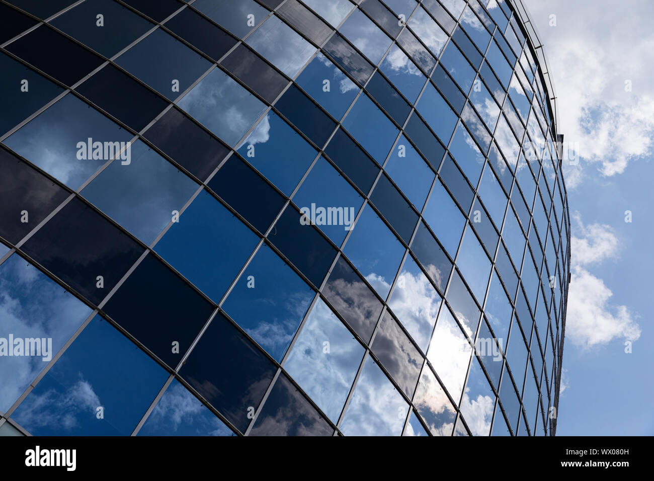 Ground diagonal view of blue sky reflection on glass building facade ...
