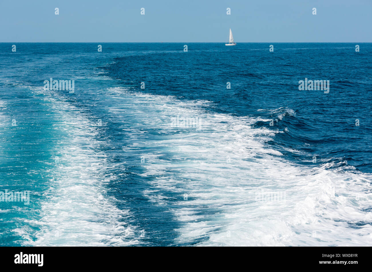 Trace on water surface in the sea and sailing vessel in far Stock Photo ...