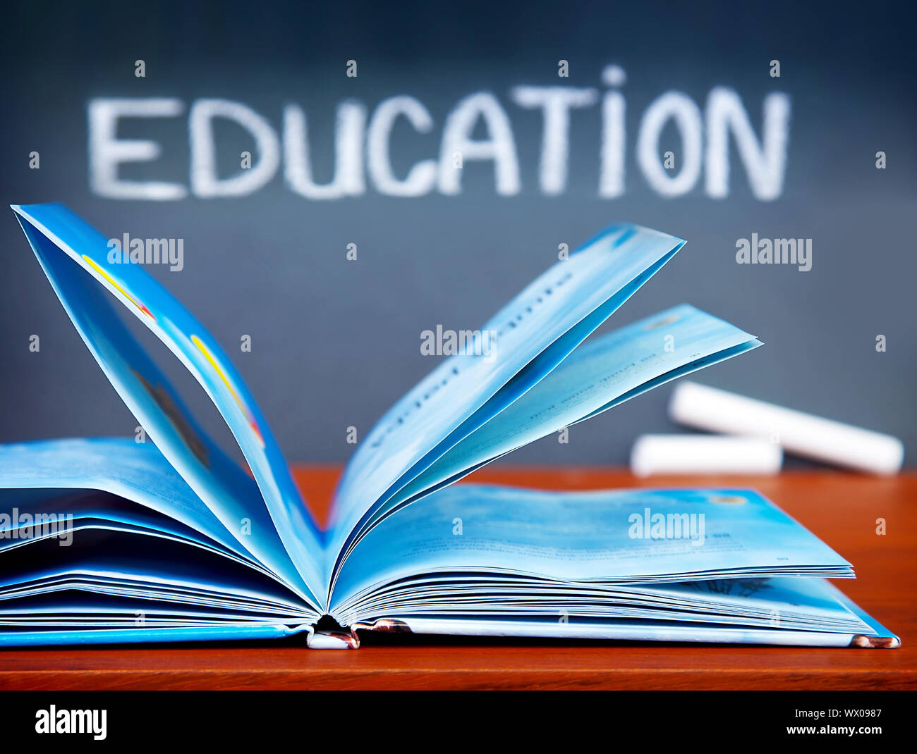 Education concept, open book on the desk in the classroom, chalkboard ...