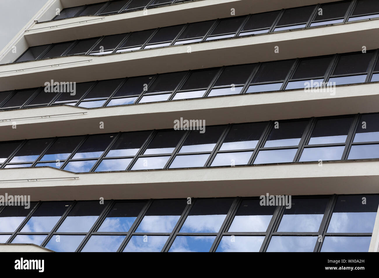 Ground view of glass square windows on white building facade with sky ...