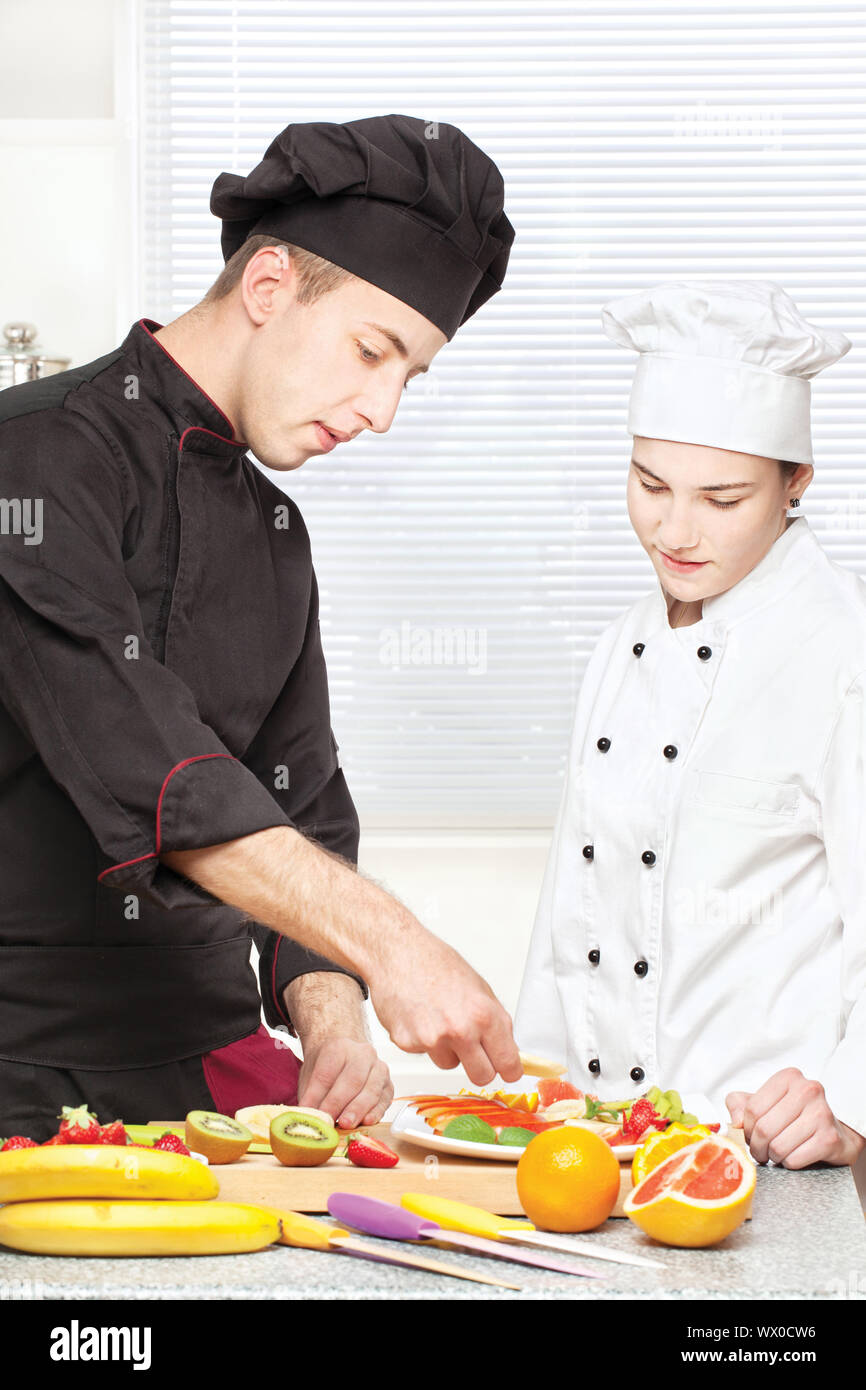 Senior chef teaches young chef to decorate fruit plate in kitchen Stock ...