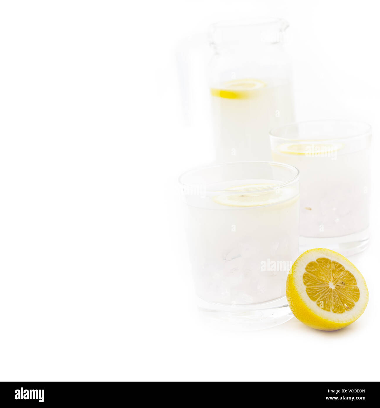 fresh lemonade drink with lemon slice closeup and pitcher carafe ...