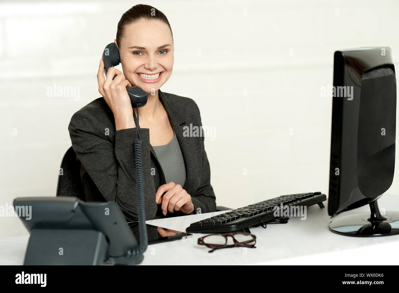 Cheerful secretary advising her client over a phone call isolated ...