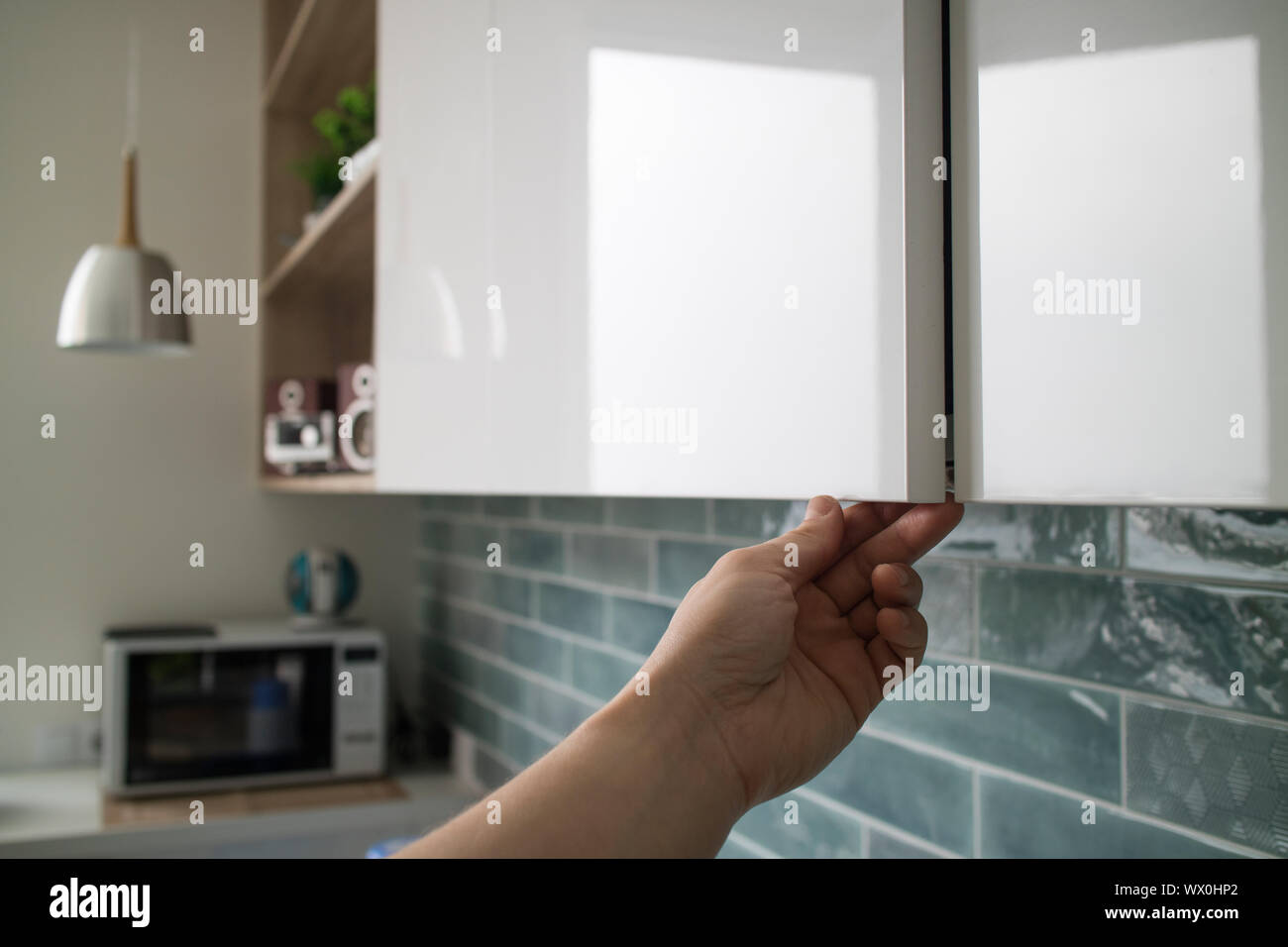 kitchen cabinet with doors without handles, the man's hand shows how ...
