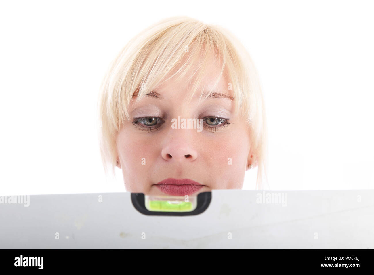 Attractive blonde woman looking at spirit level isolated on white Stock ...
