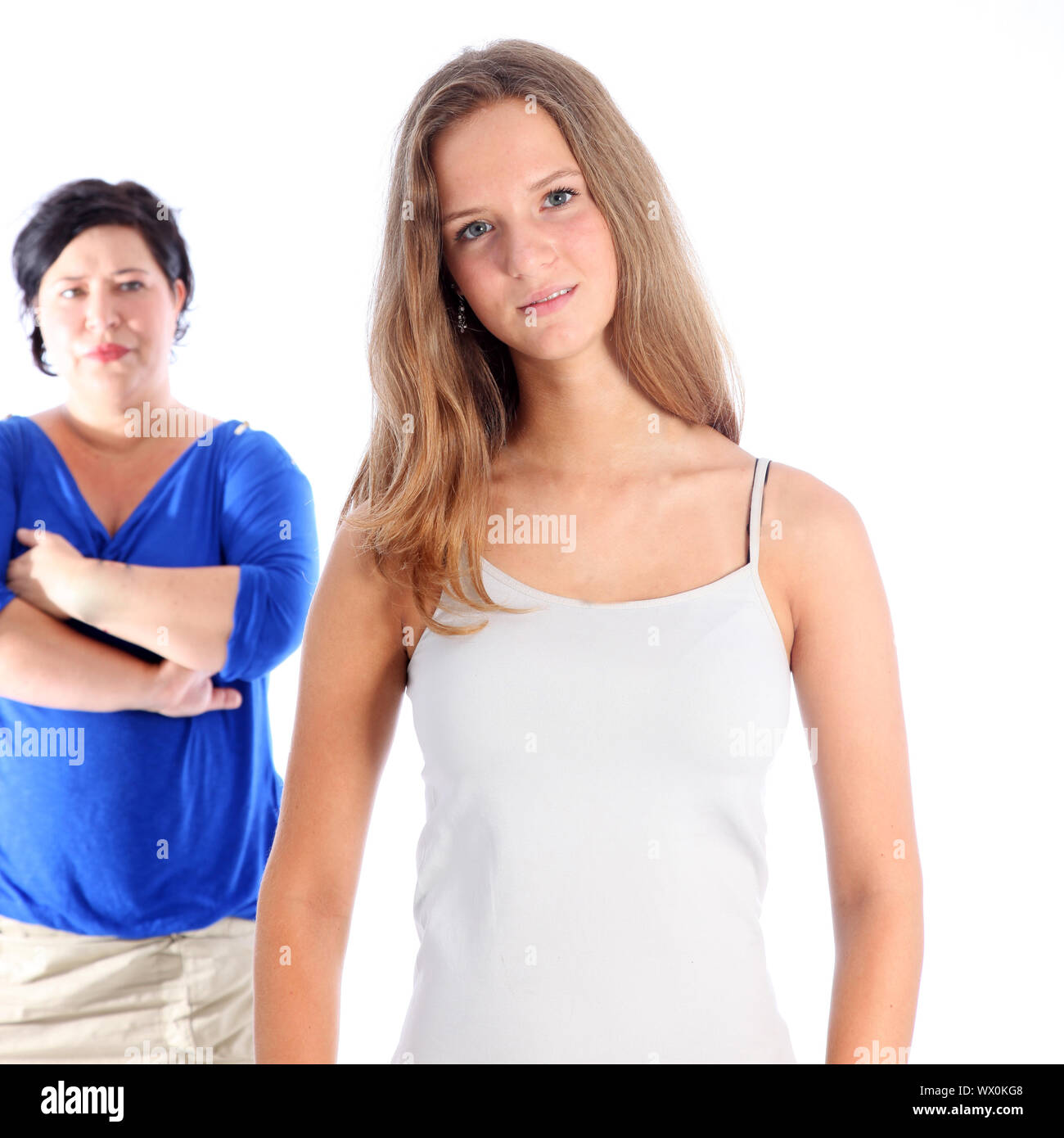 Mother standing watching her daughter with a grim expression and folded ...