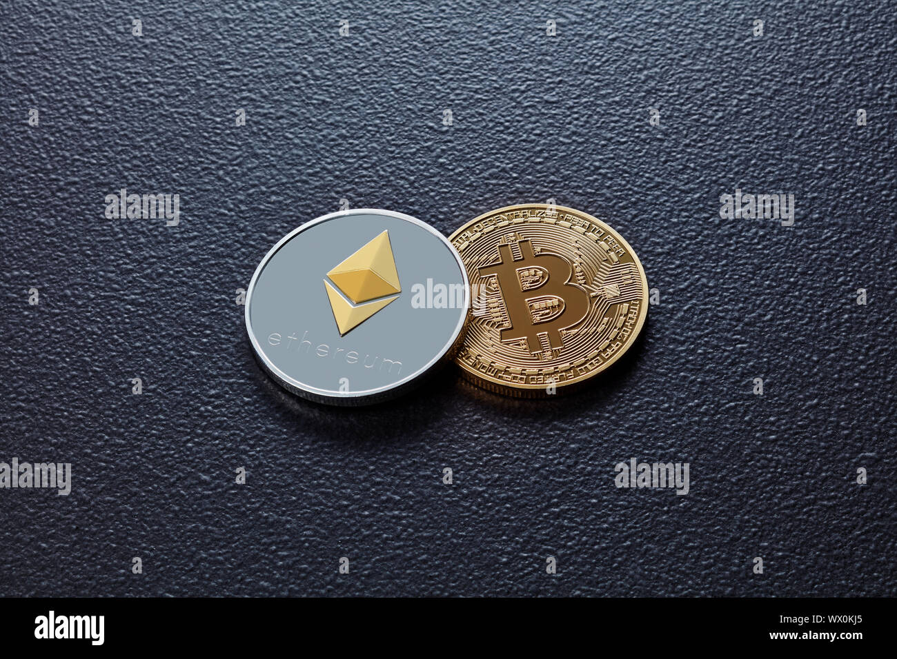 Two coins of crypto currency ETH, BTC on a black concrete background ...