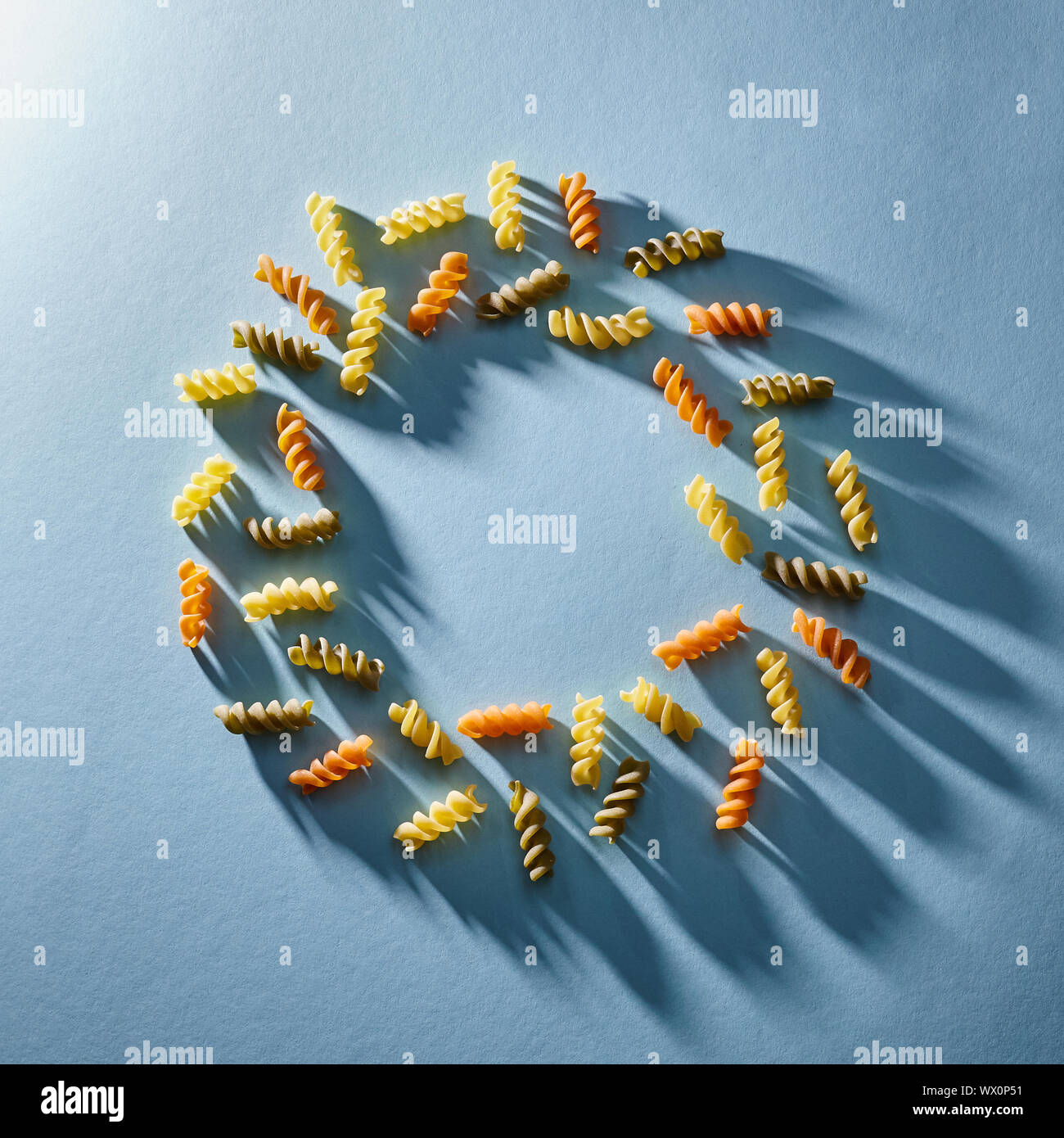 Frame in the form of a circle of multi-colored pasta on a blue ...