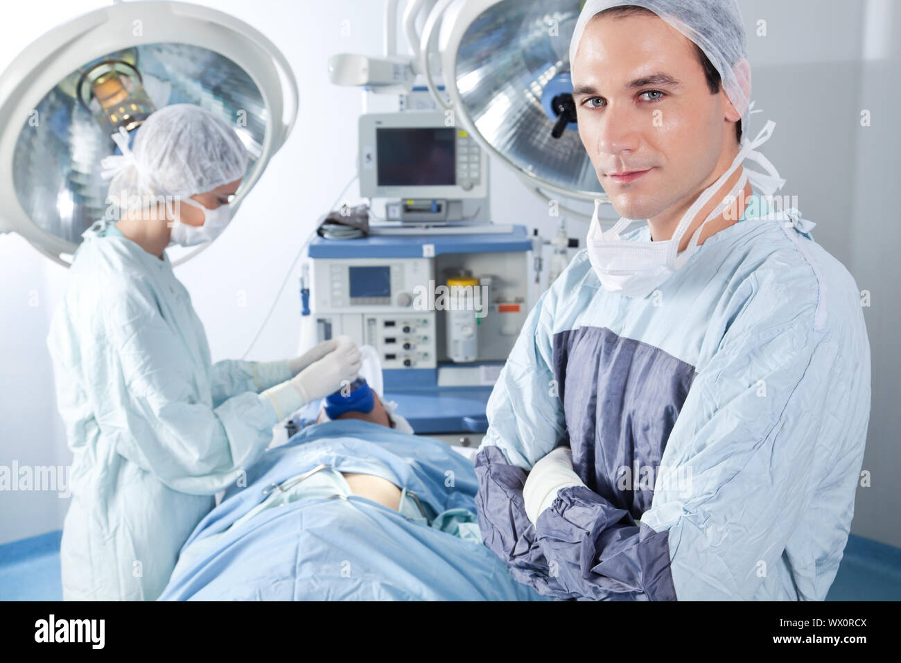 Portrait of male surgeon while nurse applying gas mask to the patient ...