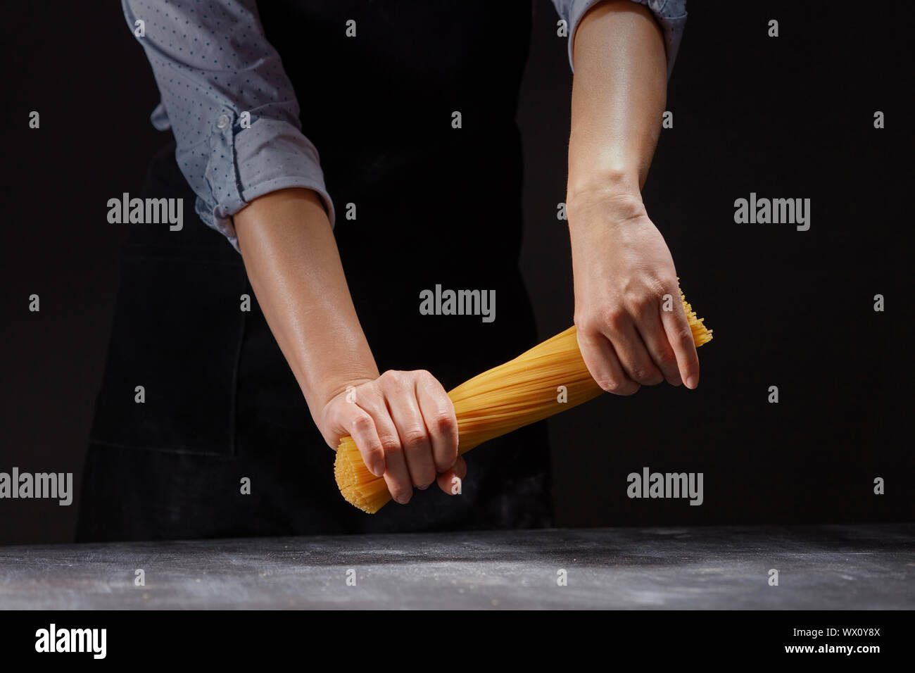 chef in an apron breaks a handful of raw Italian spaghetti Stock Photo ...