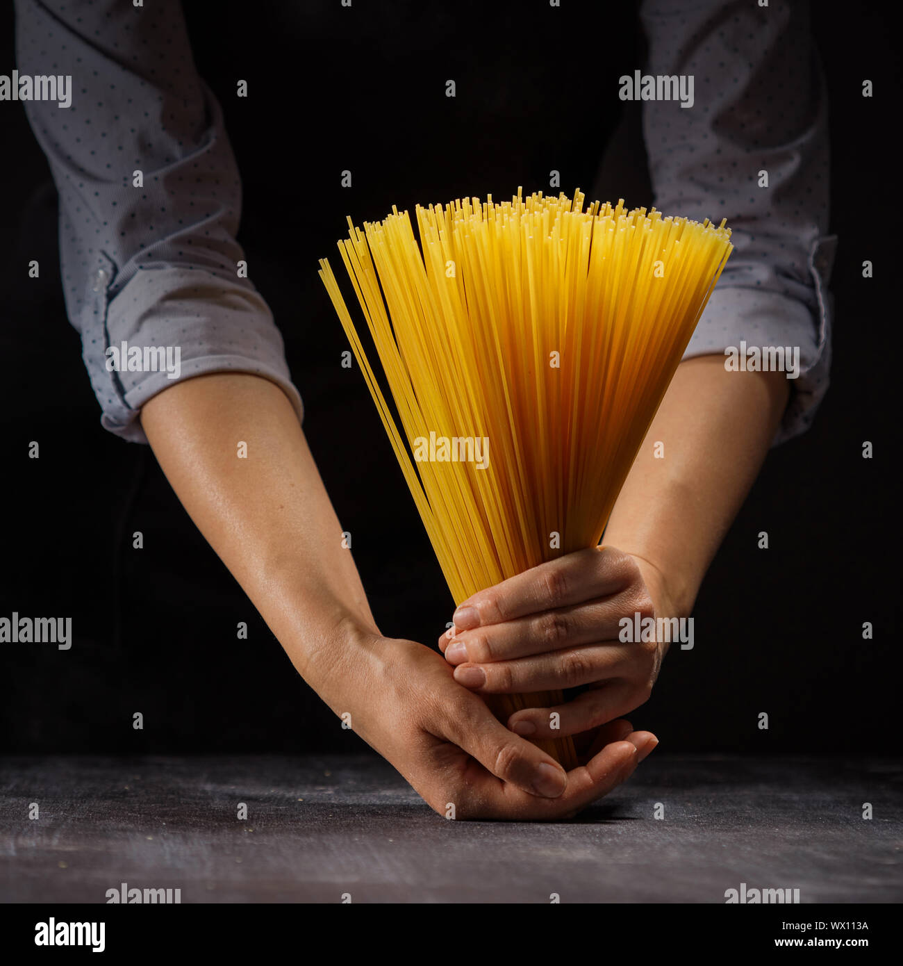 view bunch of raw spaghetti in female hands on black wood vintage table ...