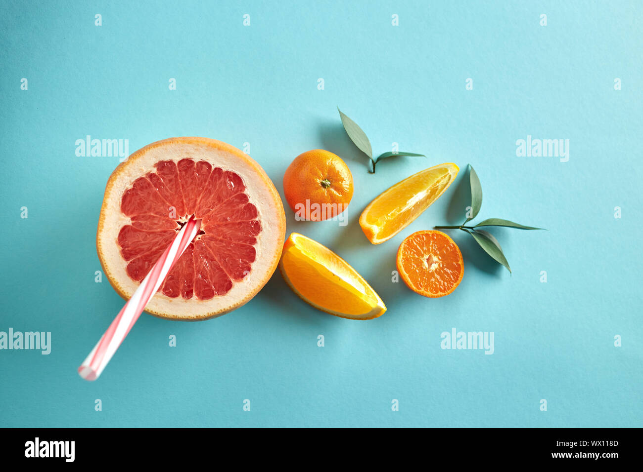 Different citrus with straws and leaves on a blue paper background top ...
