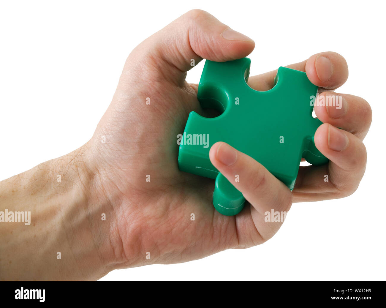 Hand holding a slice of a puzzle of green colour on a white background ...