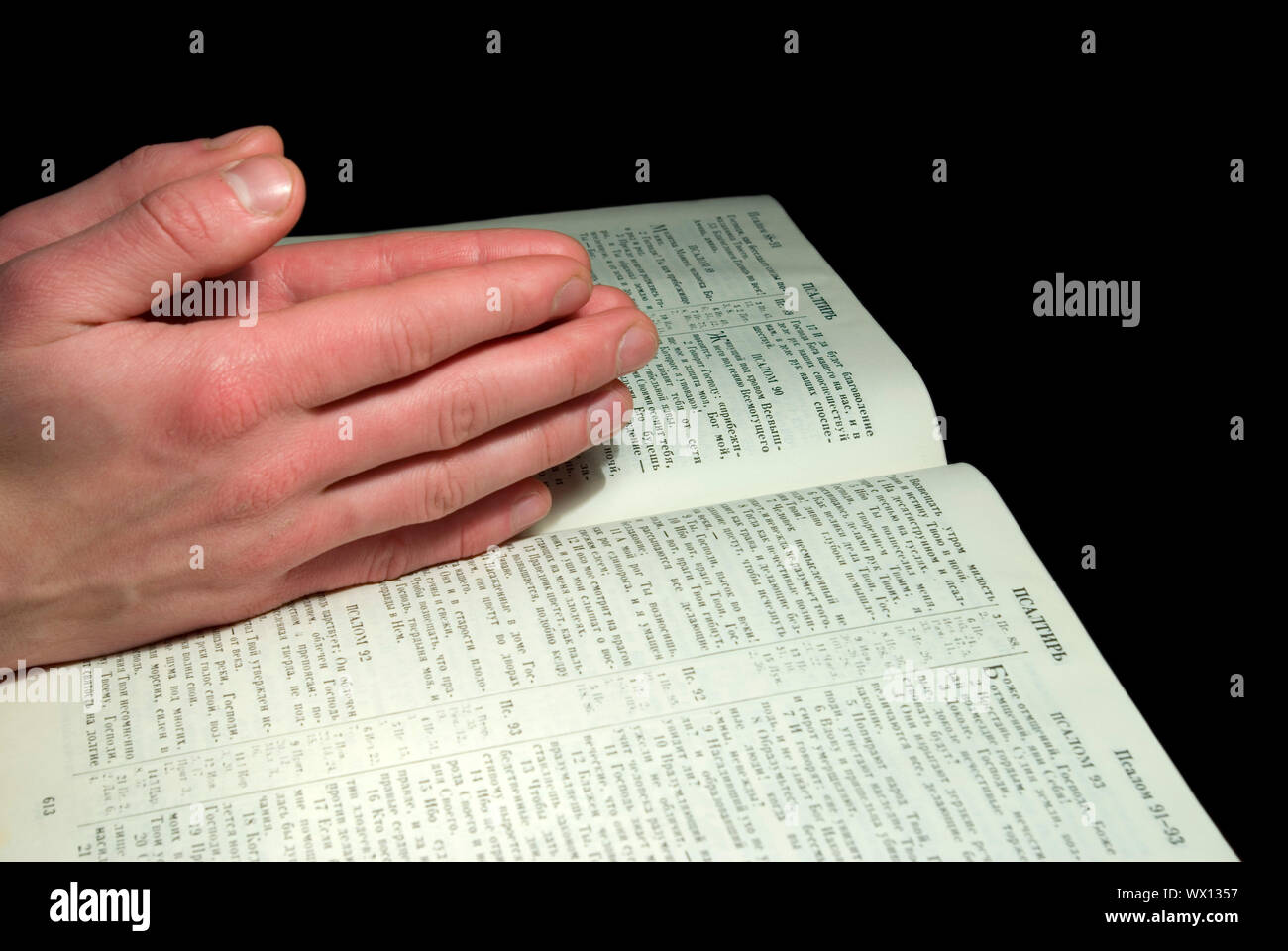 A mans hands clasped in prayer over a Bible Stock Photo - Alamy
