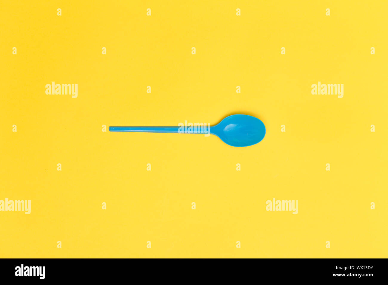 Single blue disposable spoon over a yellow background Stock Photo - Alamy
