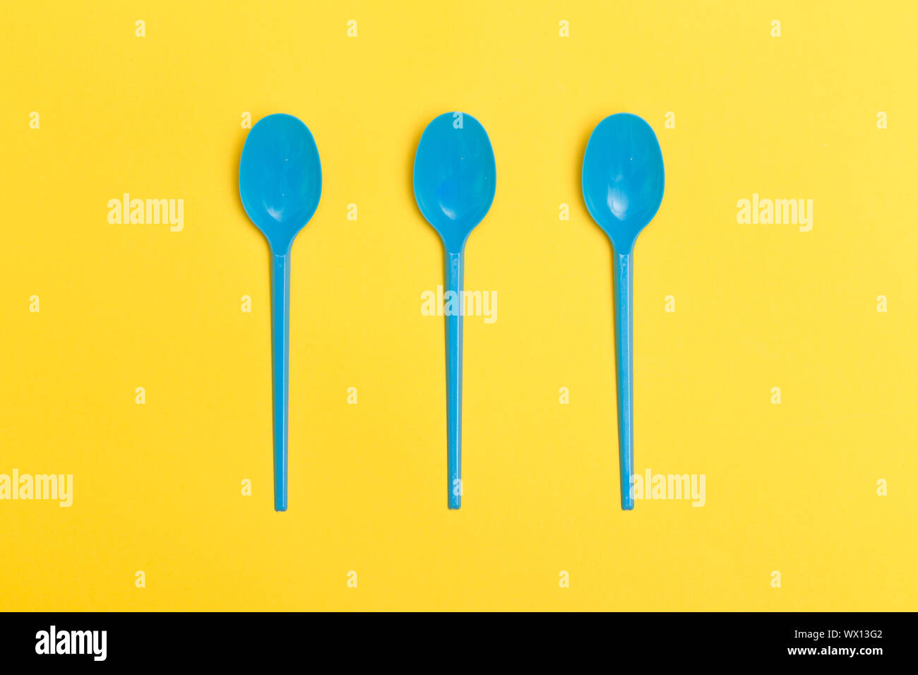 Three blue disposable plastic spoons over a yellow background Stock ...