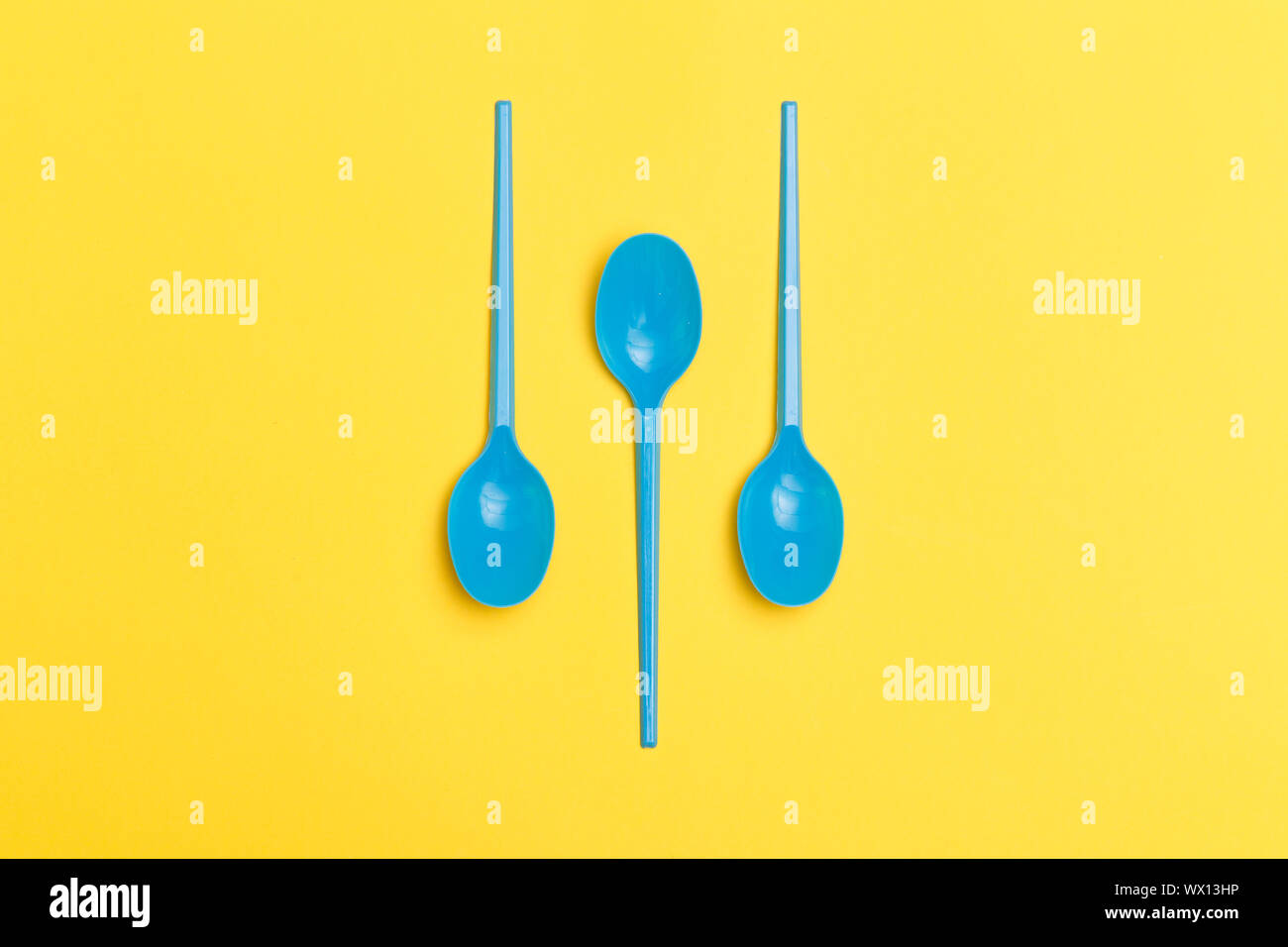 Three blue disposable plastic spoons over a yellow background Stock ...