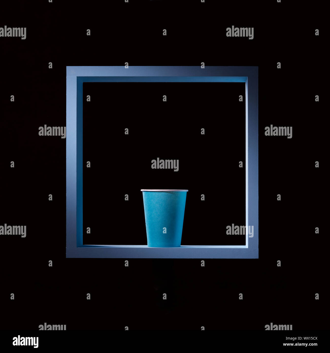 Blue paper cup in a blue square frame on a black square background ...