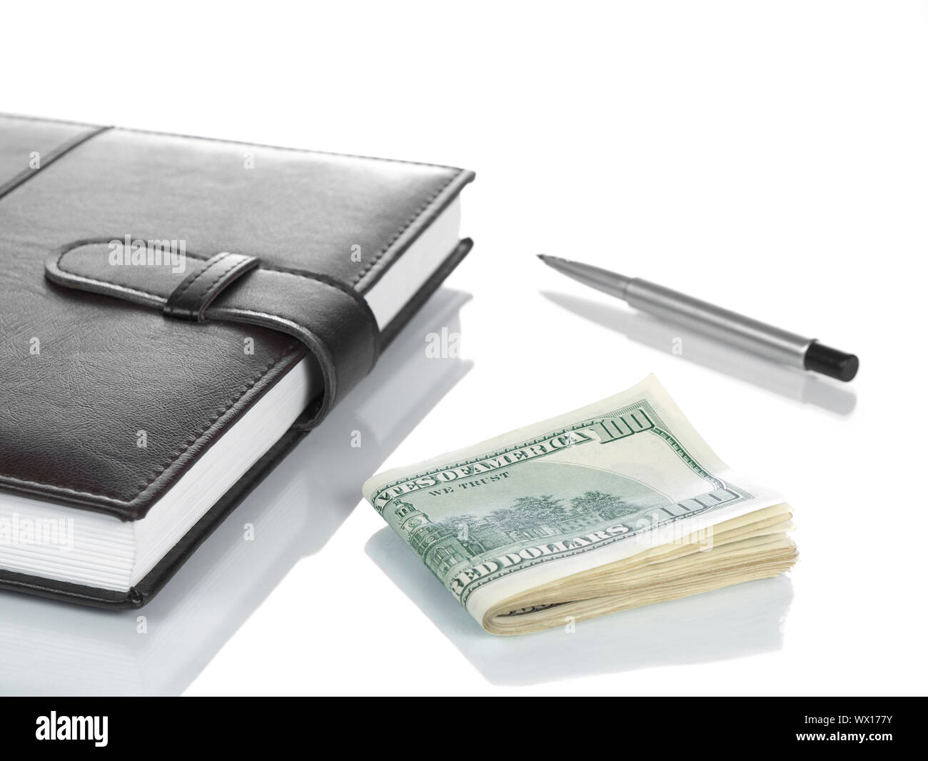 A booknote with several hundred dollar bills and a pen, isolated on ...