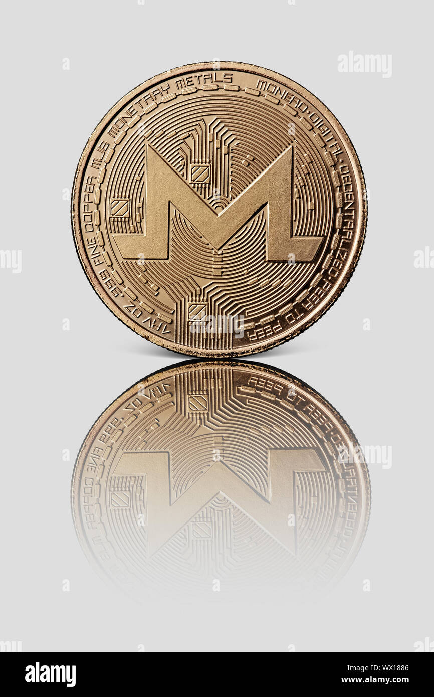 Gold Monero coin is reflected on a white glossy background. Modern way ...