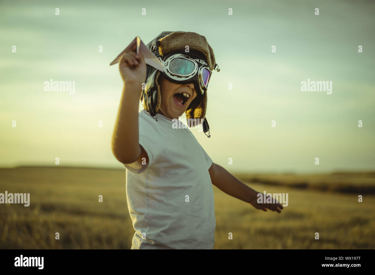 Happy boy at sunset playing at being aviator, he wears pilot glasses of ...