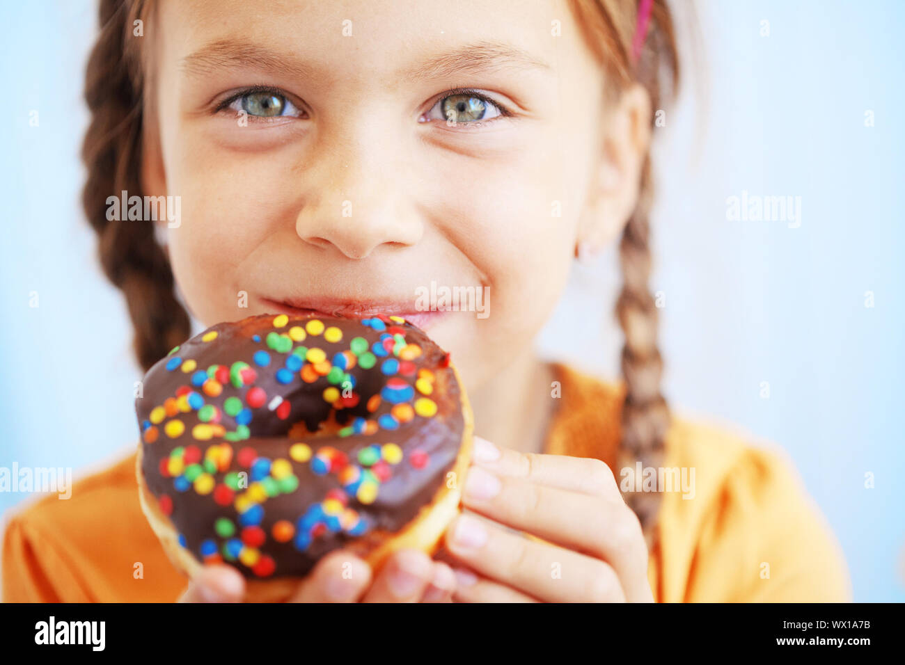 Cute kid girl eating sweet donuts Stock Photo - Alamy