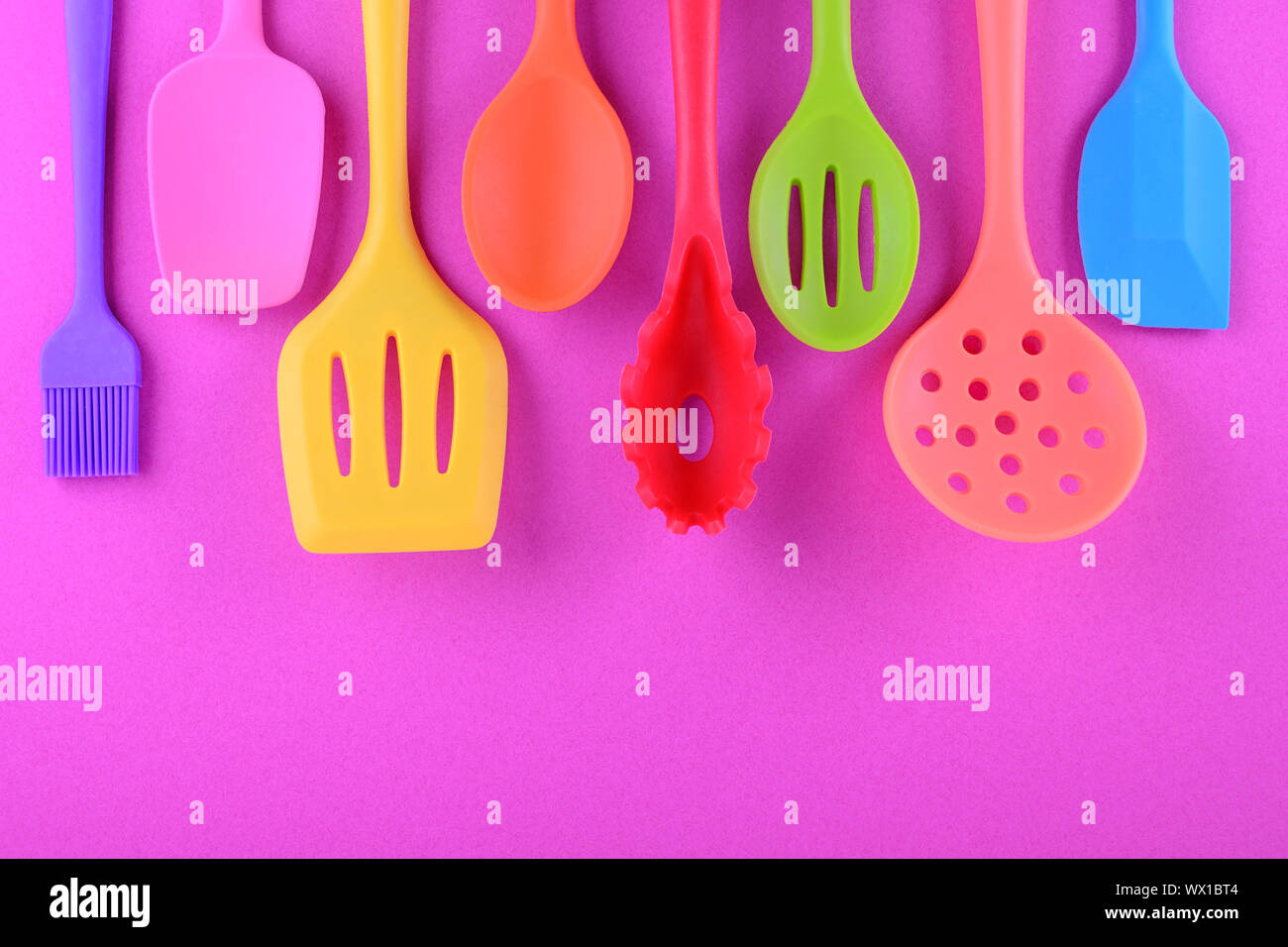 different multi colored kitchen utensils on purple background, flat lay ...