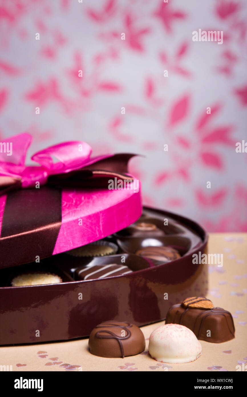 Luxury chocolates in a box with pink satin lid, shallow depth of field ...