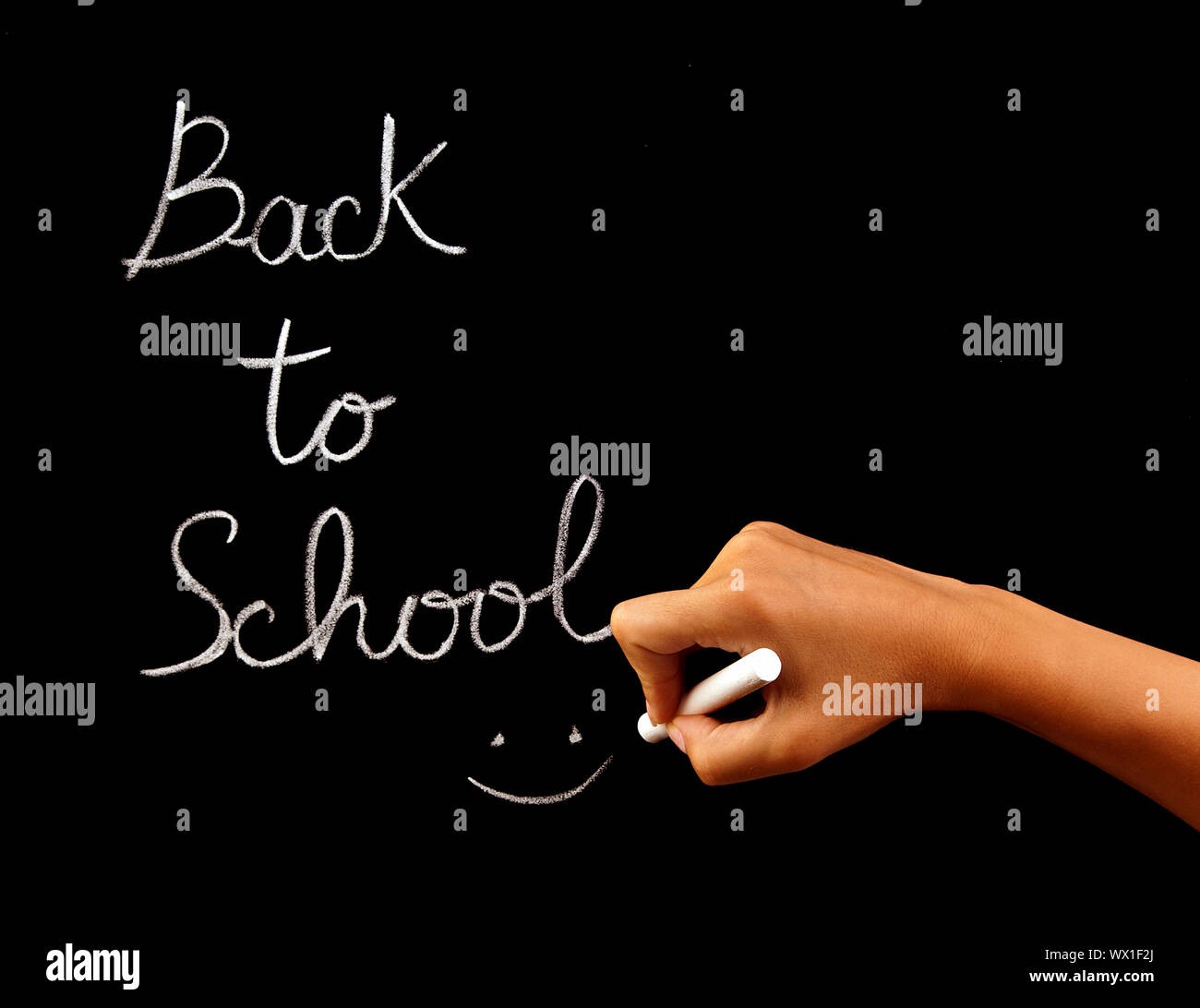 Handwriting phrase "back to school" on blackboard in classroom ...