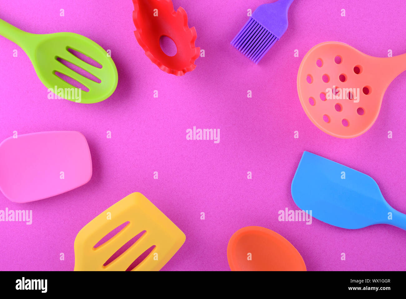 different multi colored kitchen utensils on purple background, flat lay ...