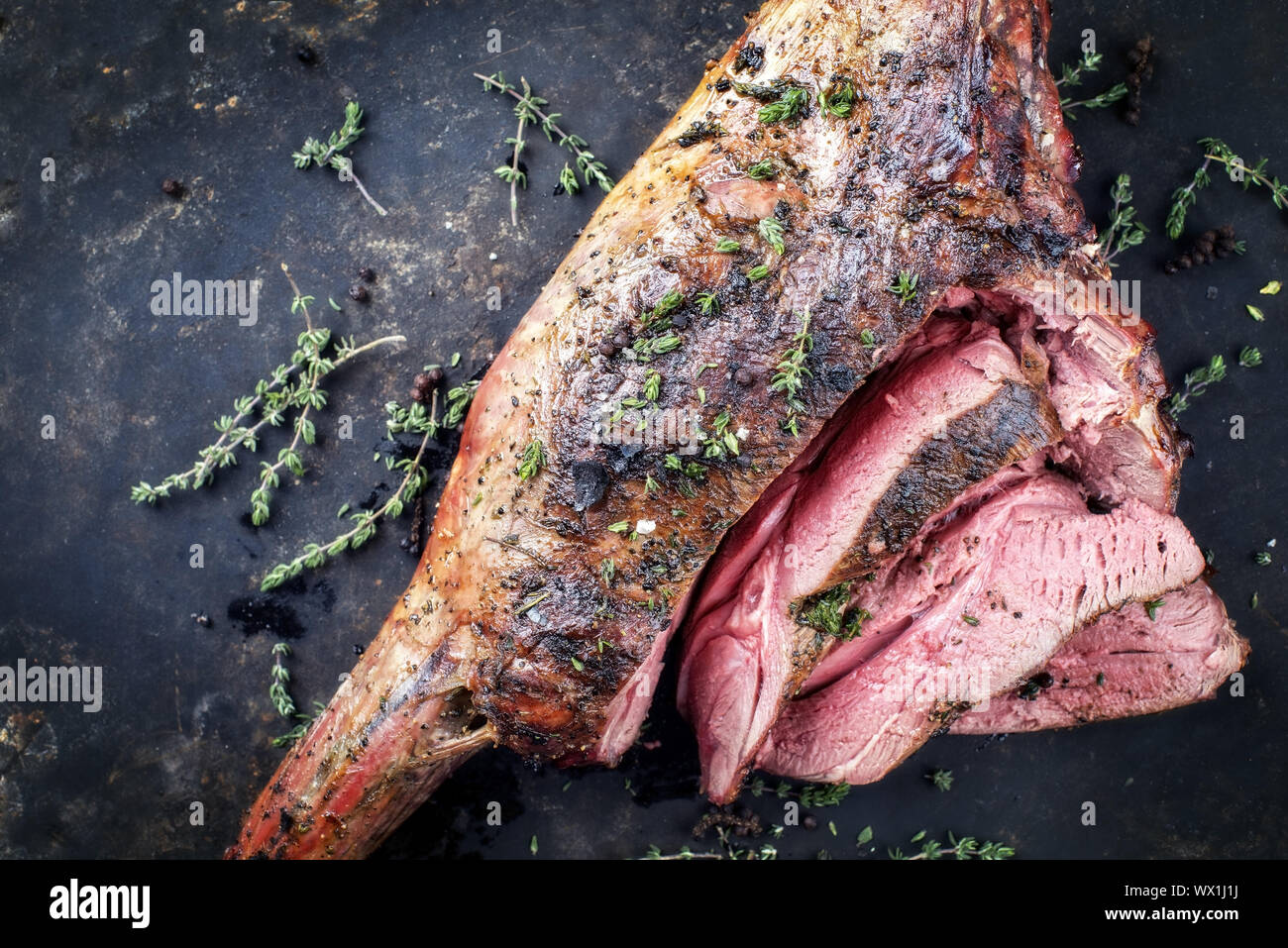 Marinated barbecue aged leg of venison sliced with herbs as top view on ...