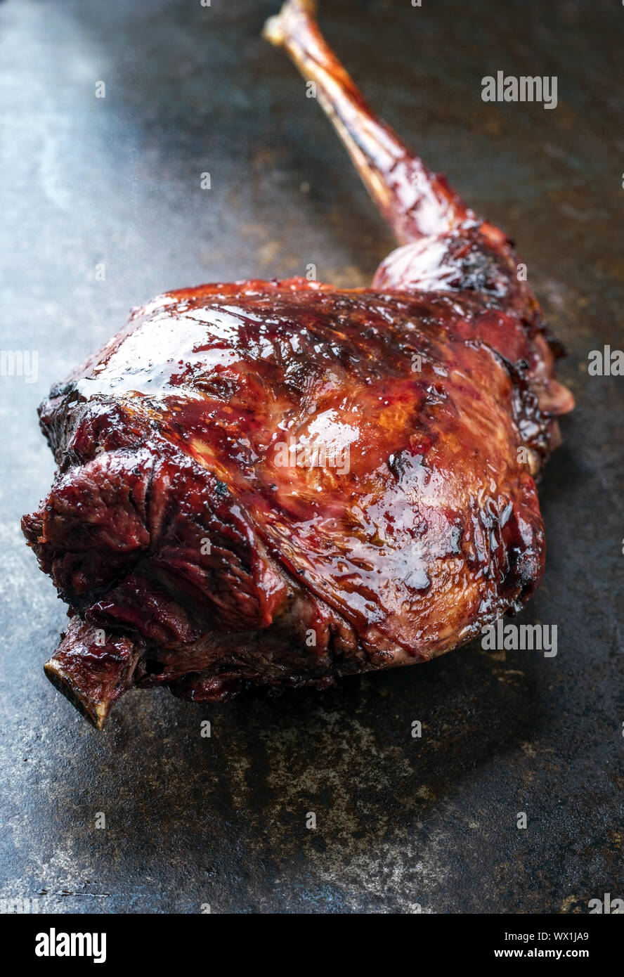 Marinated barbecue aged leg of venison with bone as top view on rustic ...