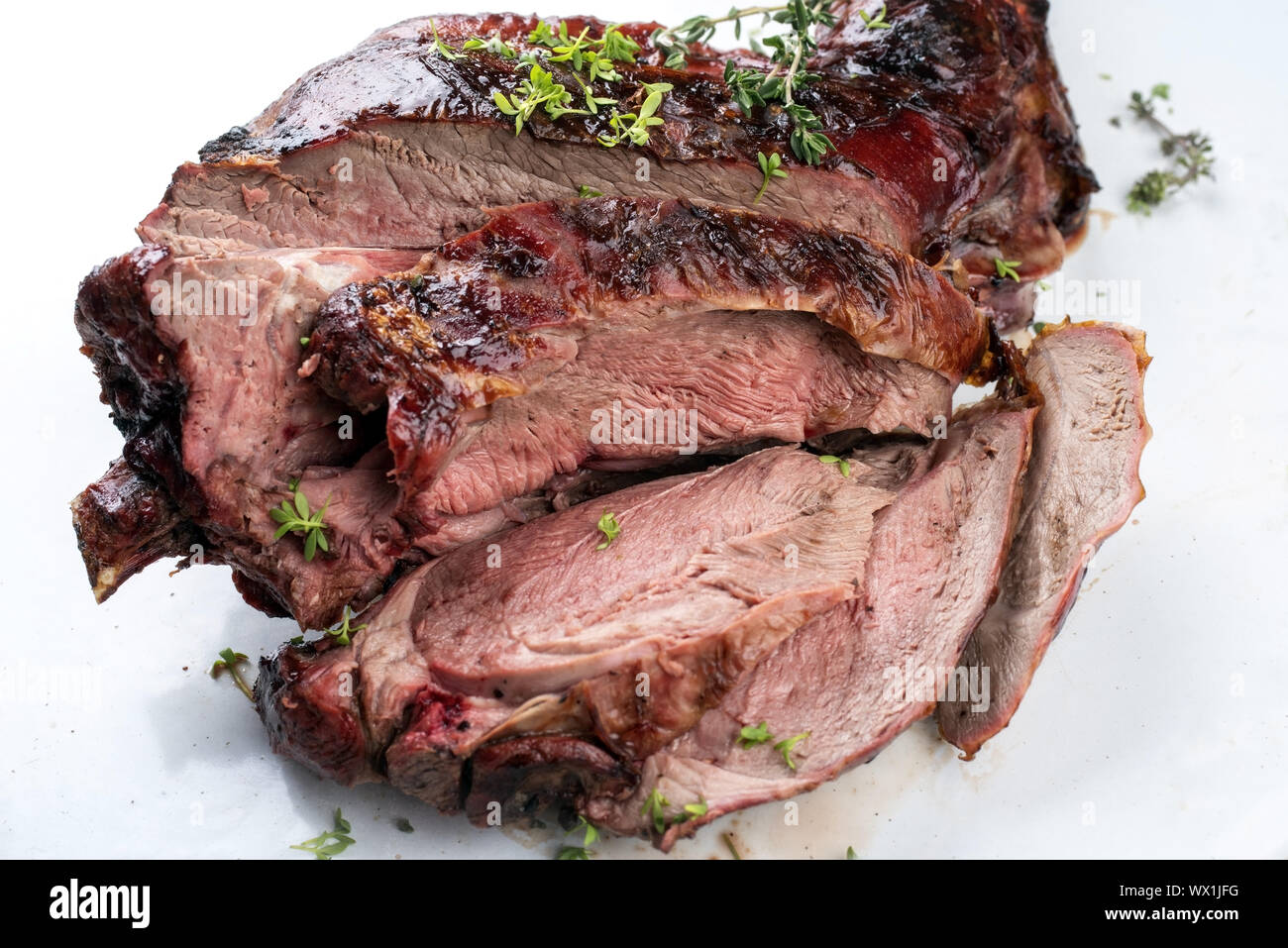 Marinated sliced barbecue aged leg of venison as close-up on white ...